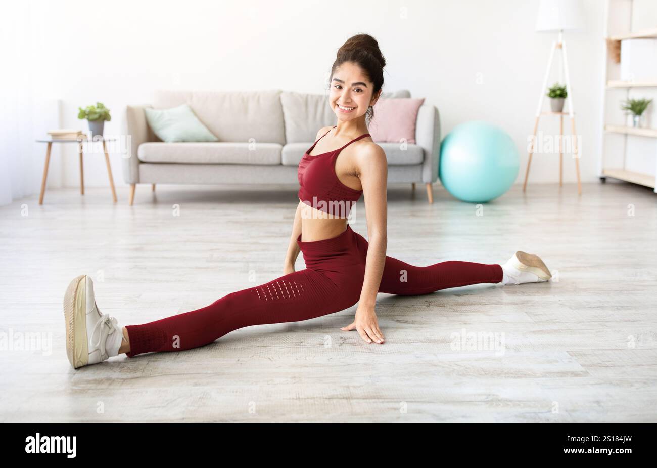 Sporty Indian woman sitting in splits, doing legs stretch, improving ...