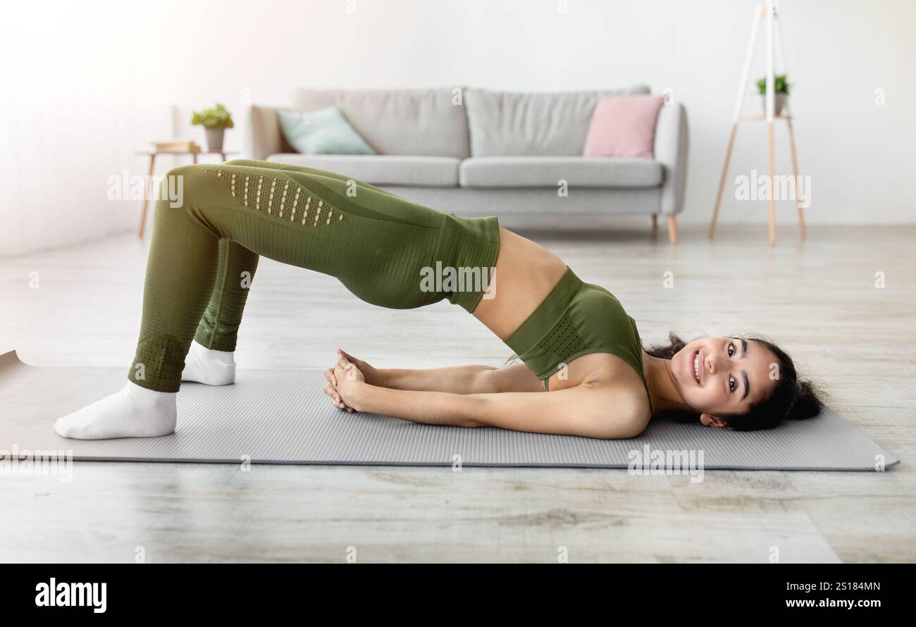 Beautiful Indian lady doing abs exercise, standing in half bridge yoga ...