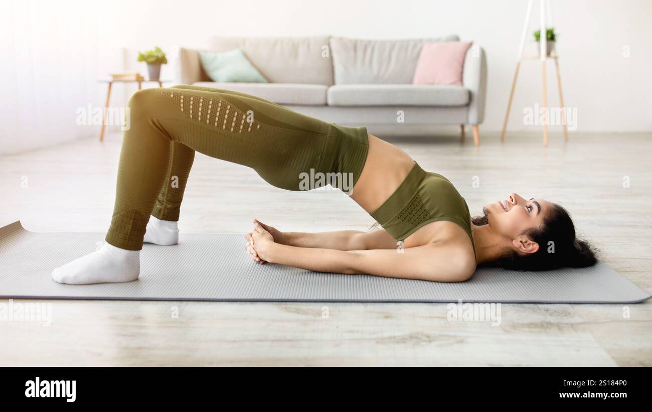Side view of Indian lady doing abs exercise, standing in half bridge ...