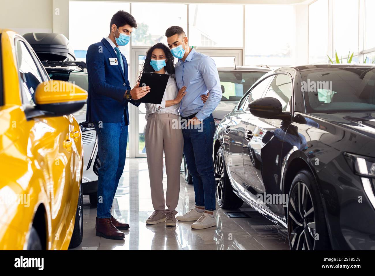 Young couple embracing while having conversation with salesman, buying ...