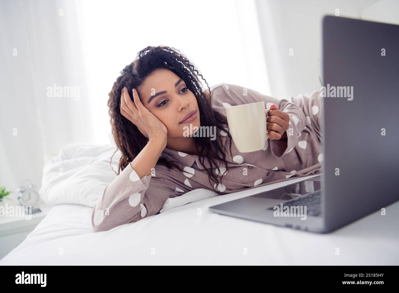 Young woman relaxing in bed with coffee, enjoying morning leisure and ...