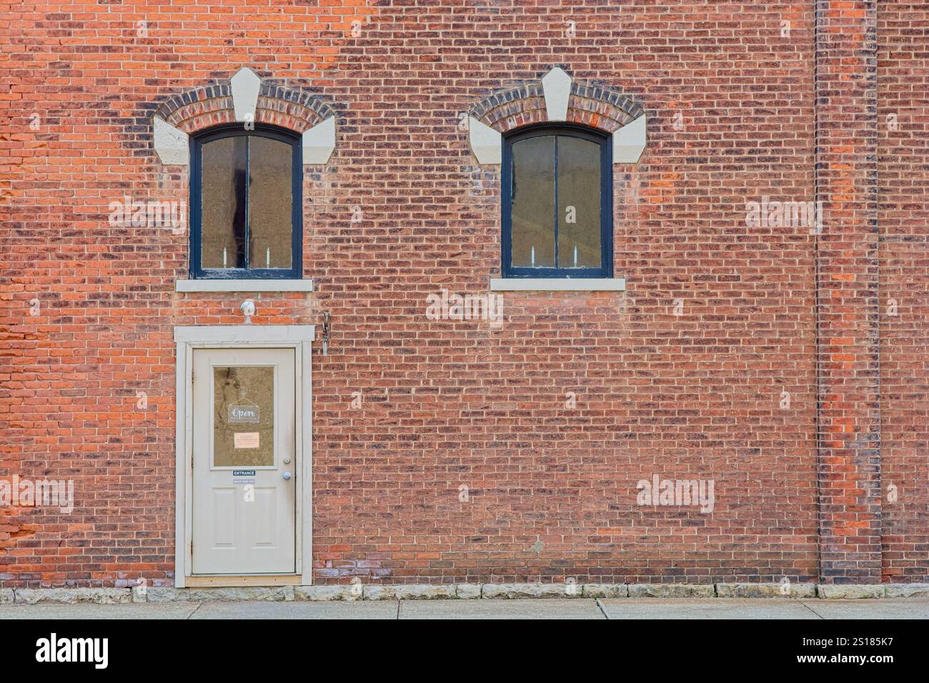 Two arched windows and doorway in wall of brick building Stock Photo ...
