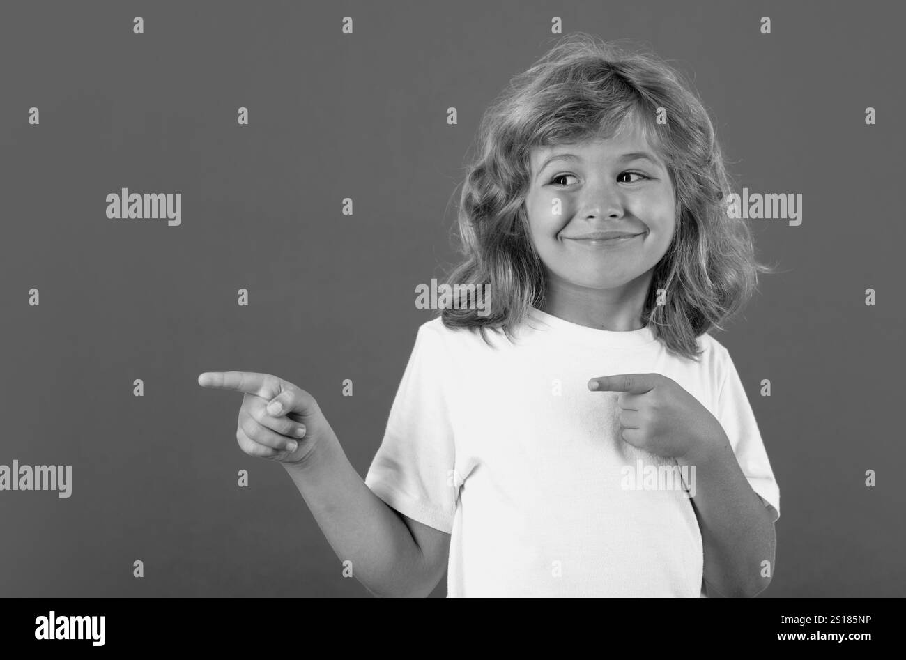 Child boy pointing away on blue isolated studio background. Portrait of ...