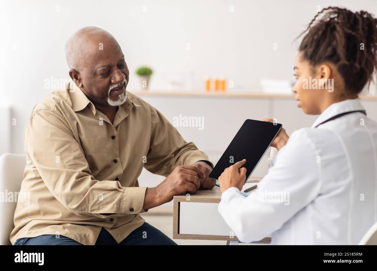 Young black doctor explaining treatment plan to male patient Stock ...