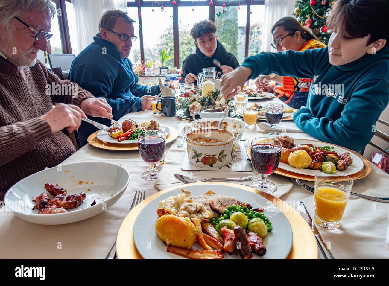 A family sit together and enjoy a roast Christmas dinner Stock Photo ...