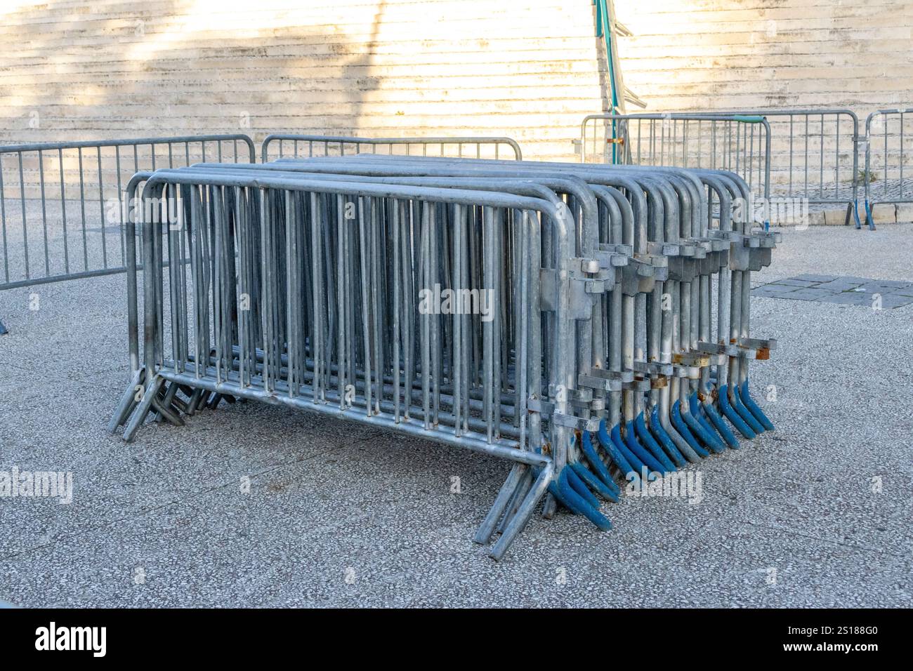 Galvanized steel crowd control barriers stacked together, ready for deployment in a public space ...