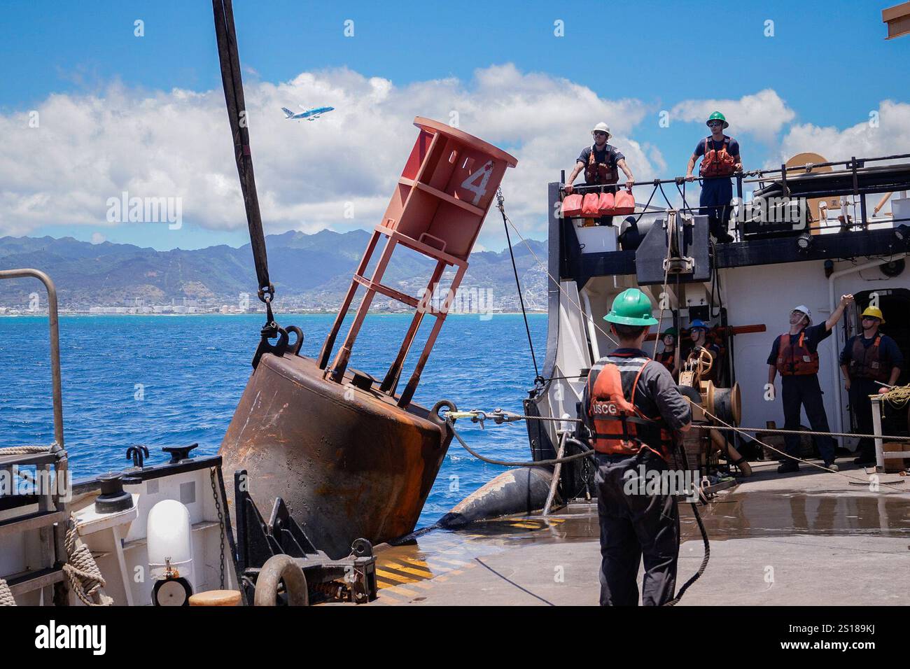 Members of the Coast Guard Cutter Juniper hoist a buoy out of the water ...