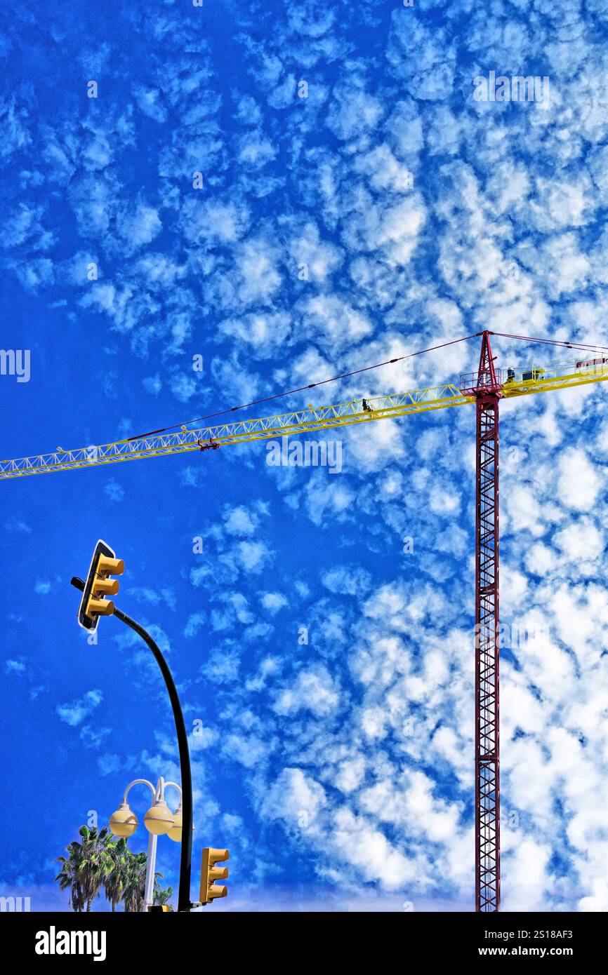 Traffic lights and large industrial building crane against blue sky and ...