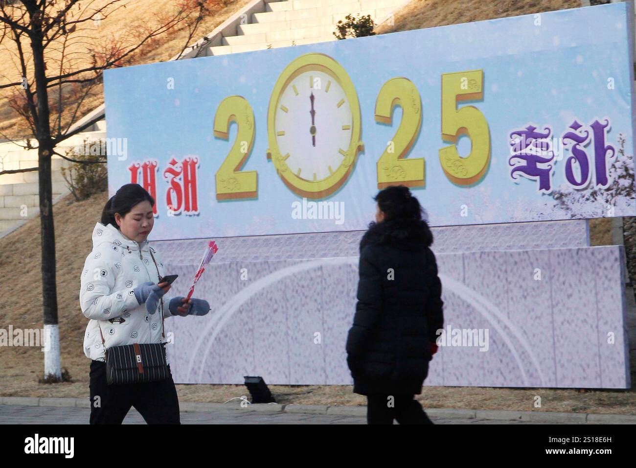 Women walk past a billboard that reads, "2025, New Year's Greetings ...