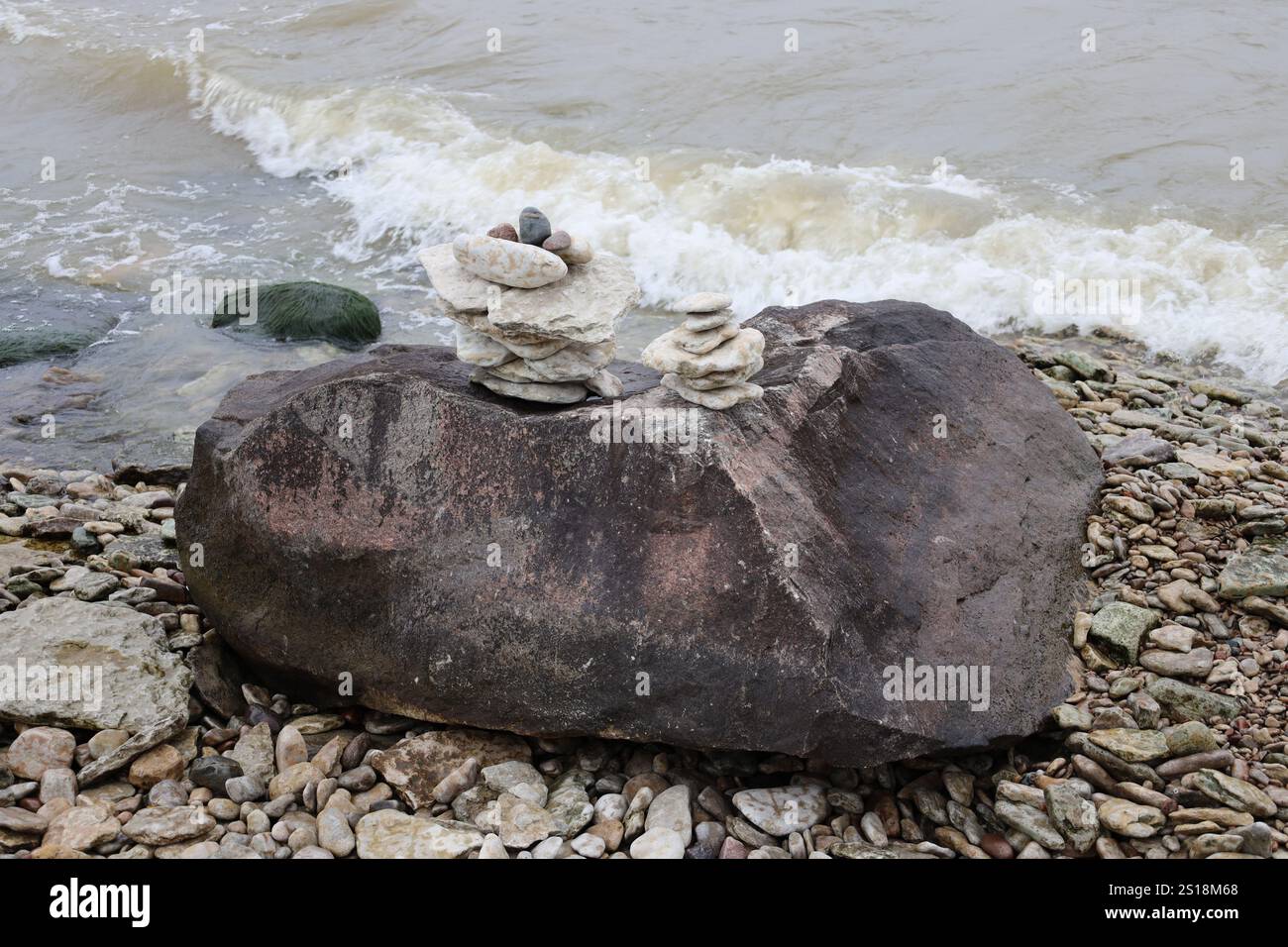 piled stone markers on boulder on lake shore Stock Photo - Alamy