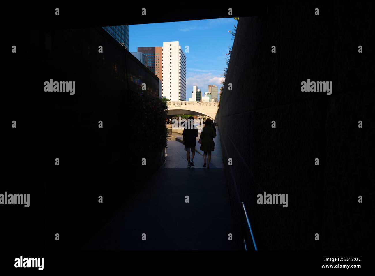 A couple in shadow, silhouette heading down the sidewalk along the ...