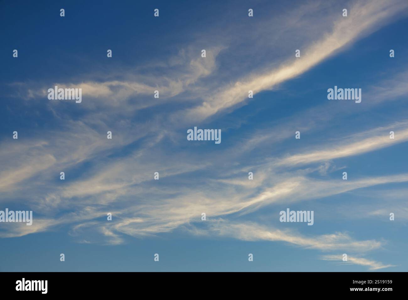 Elongated Clouds - Wispy clouds form a web like structure on a clear blue sky as they spread out ...