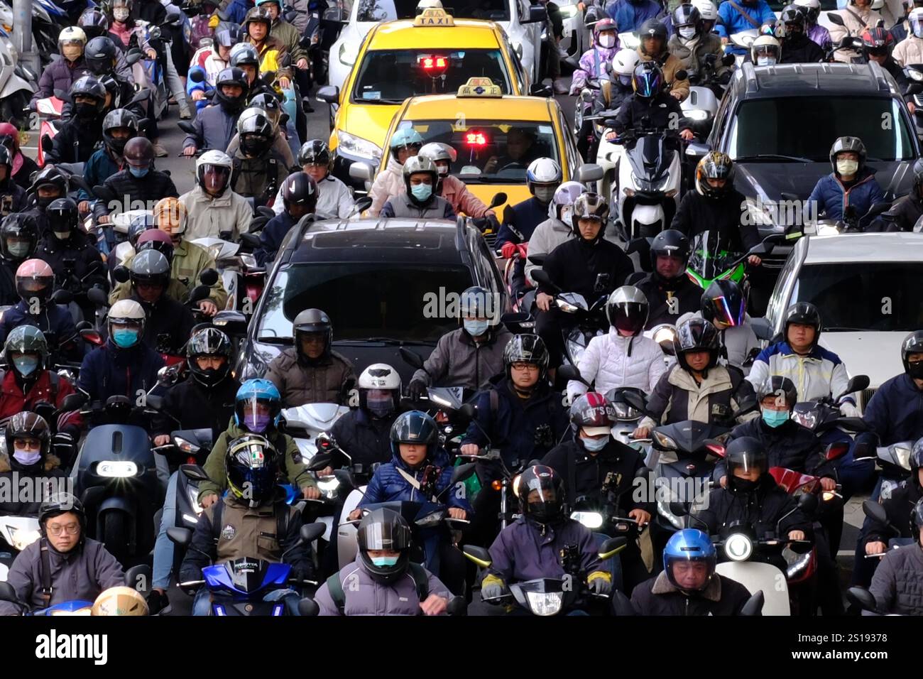 Several early morning commuters on motorbikes stop at the intersection ...
