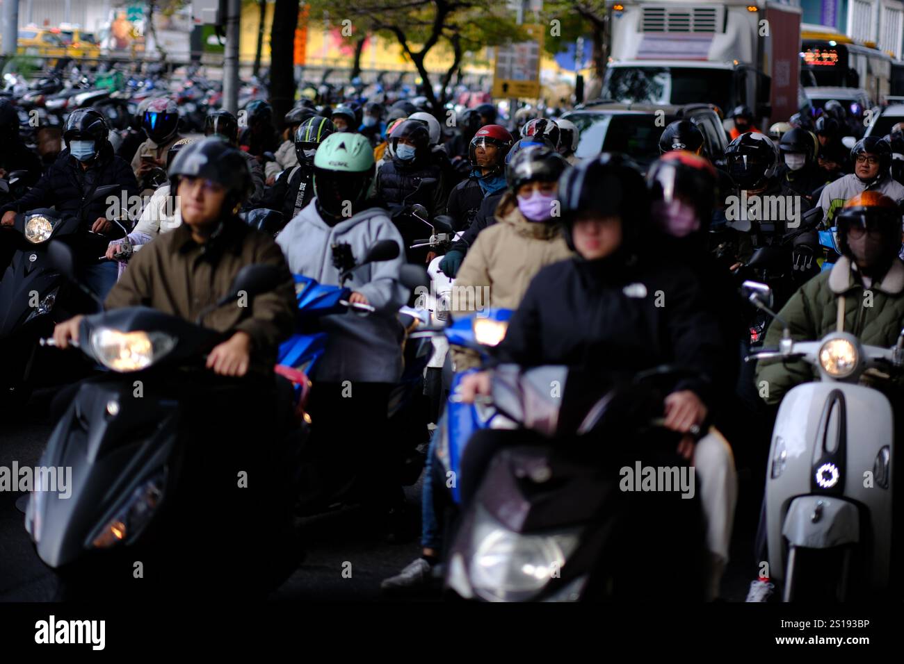 Several early morning commuters on motorbikes stop at the intersection ...
