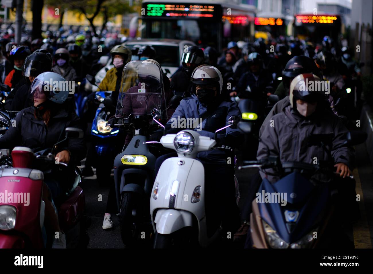 Several early morning commuters on motorbikes stop at the intersection ...