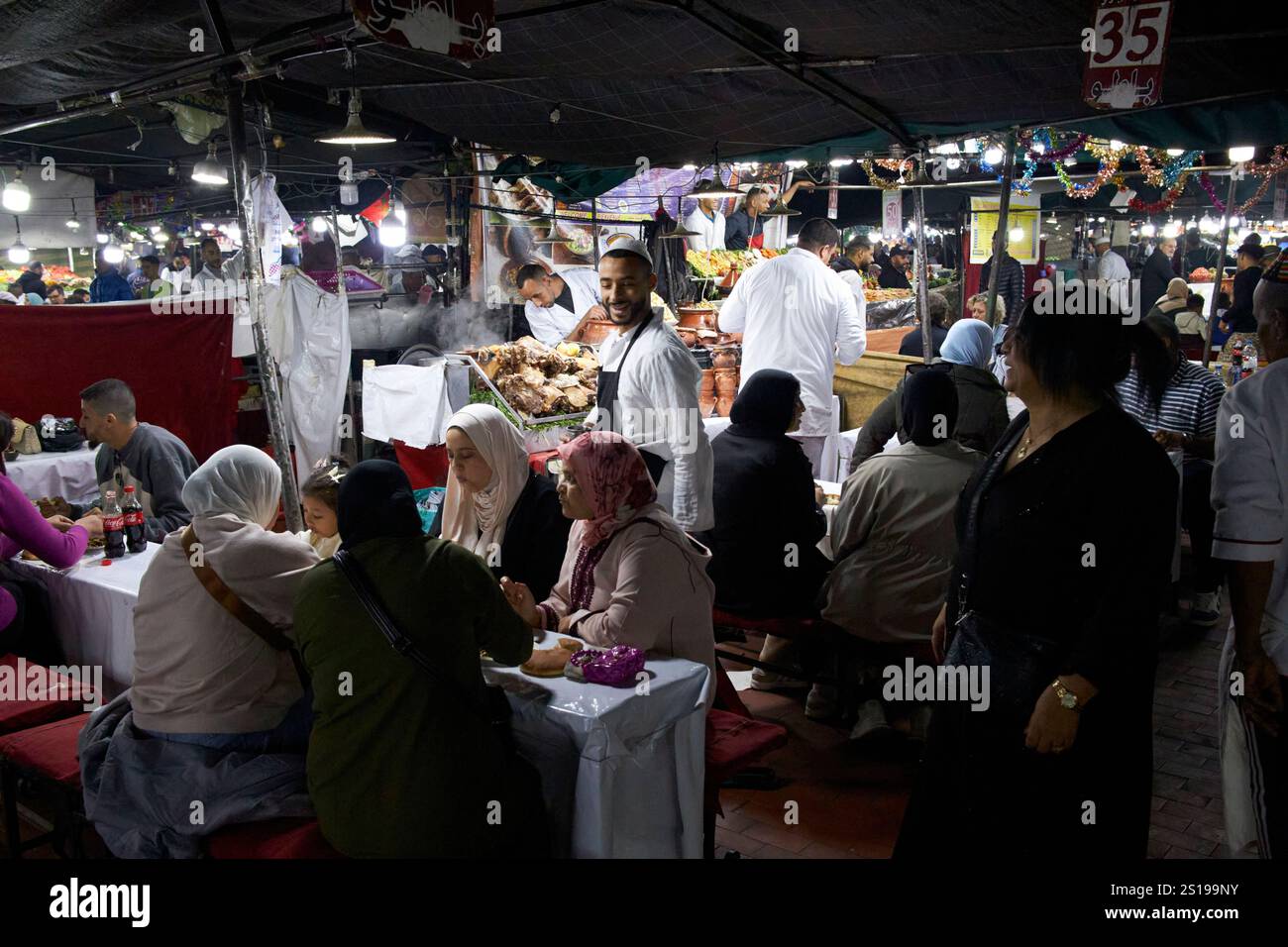 local people sitting on benches eating street food at one of the food ...