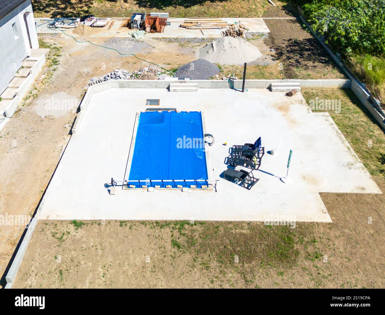 Overview of swimming pool construction with blue pool cover and ...