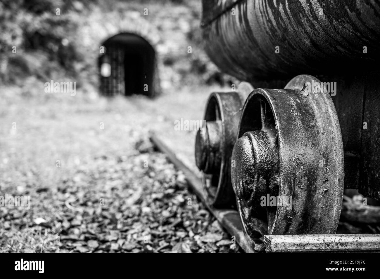 Rusty wheels of a mining truck rest on a gravel track leading to an old ...