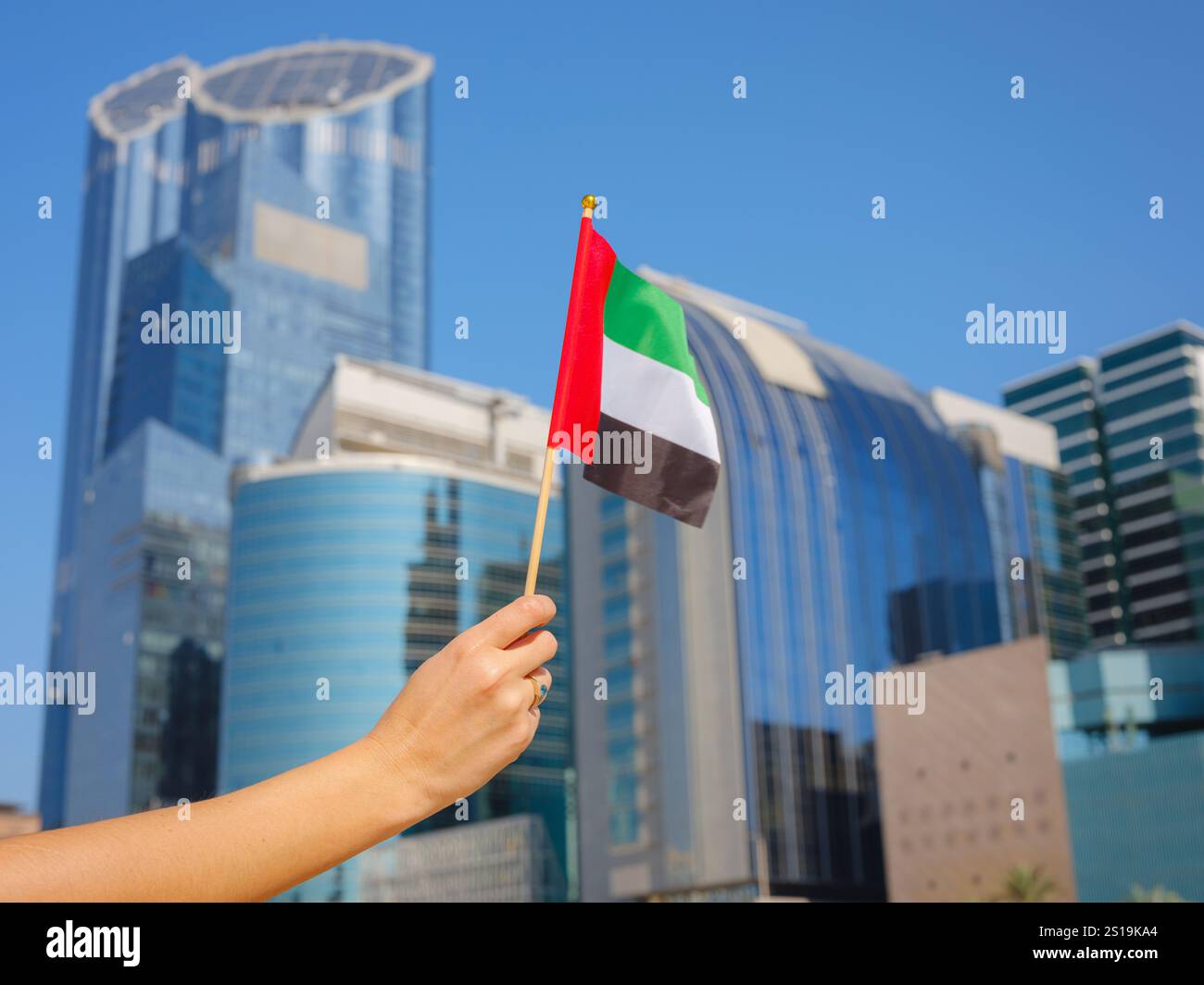 Close up of female hand holding tiny flag of UAE against Abu Dhabi ...
