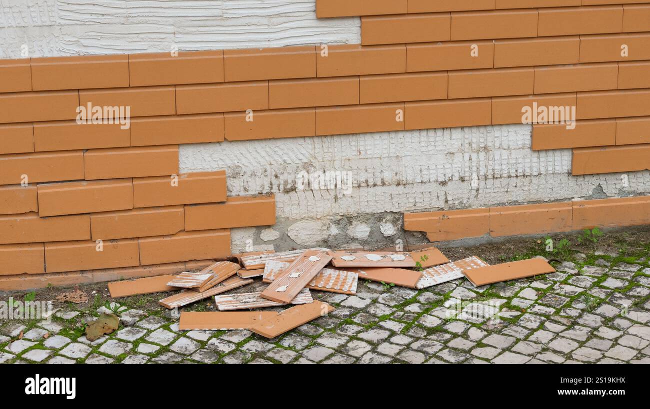 Orange tiles falling off a building facade and scattered on a ...