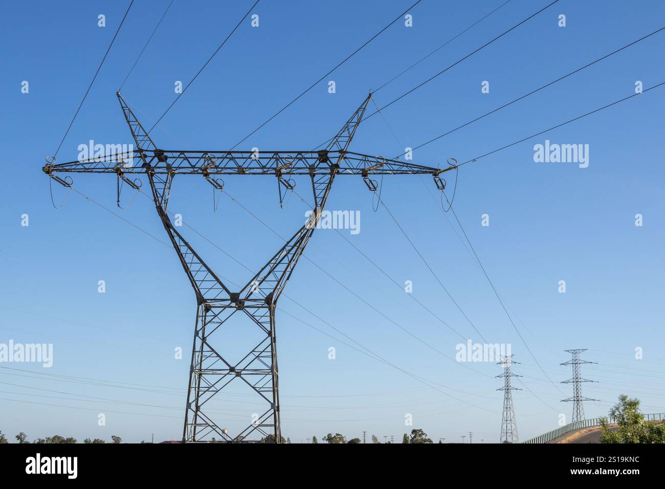 Metal electricity pylon and power lines dominating a clear blue sky ...