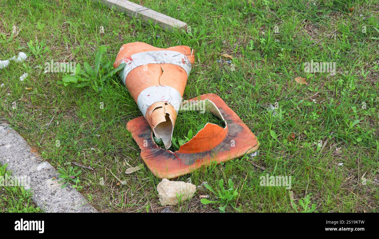 Broken traffic cone lying on grass symbolizes negligence and disregard ...