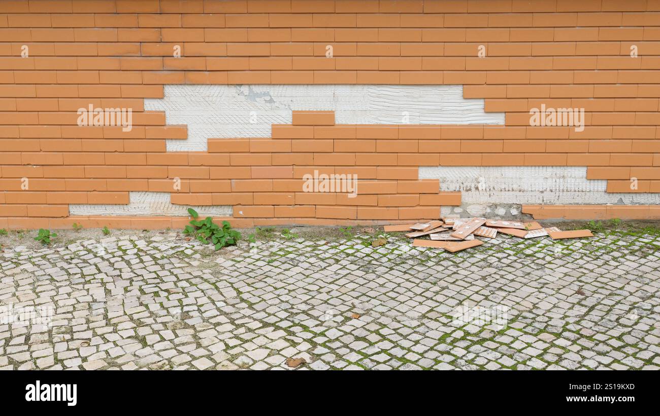 Orange brick tiles falling off a building facade and scattered on a ...