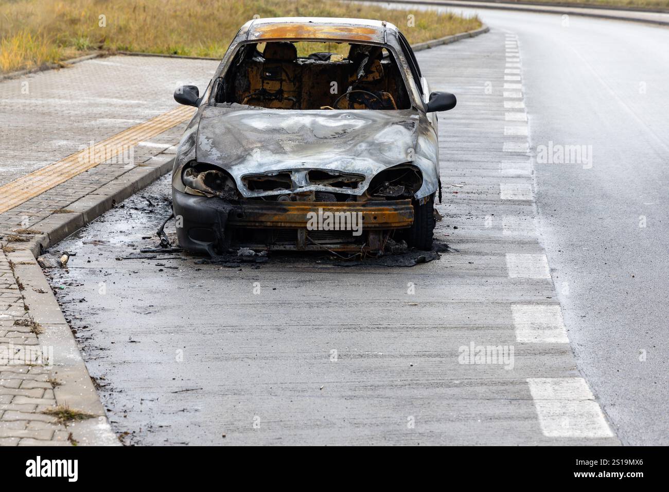 Burnt passenger car standing on the road. Vehicle with interior largely ...