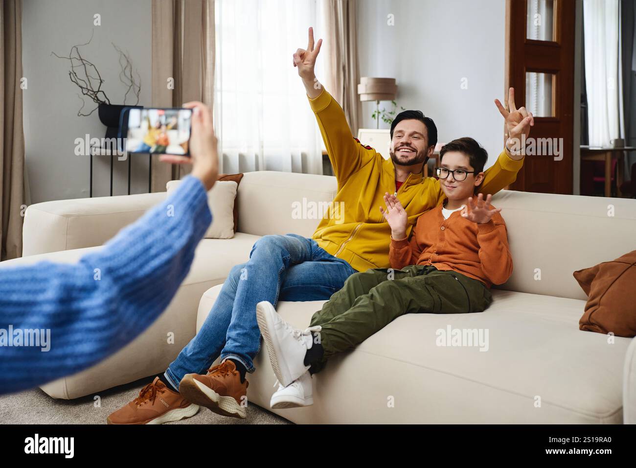 Father and son making peace signs while posing on a couch indoors Stock ...