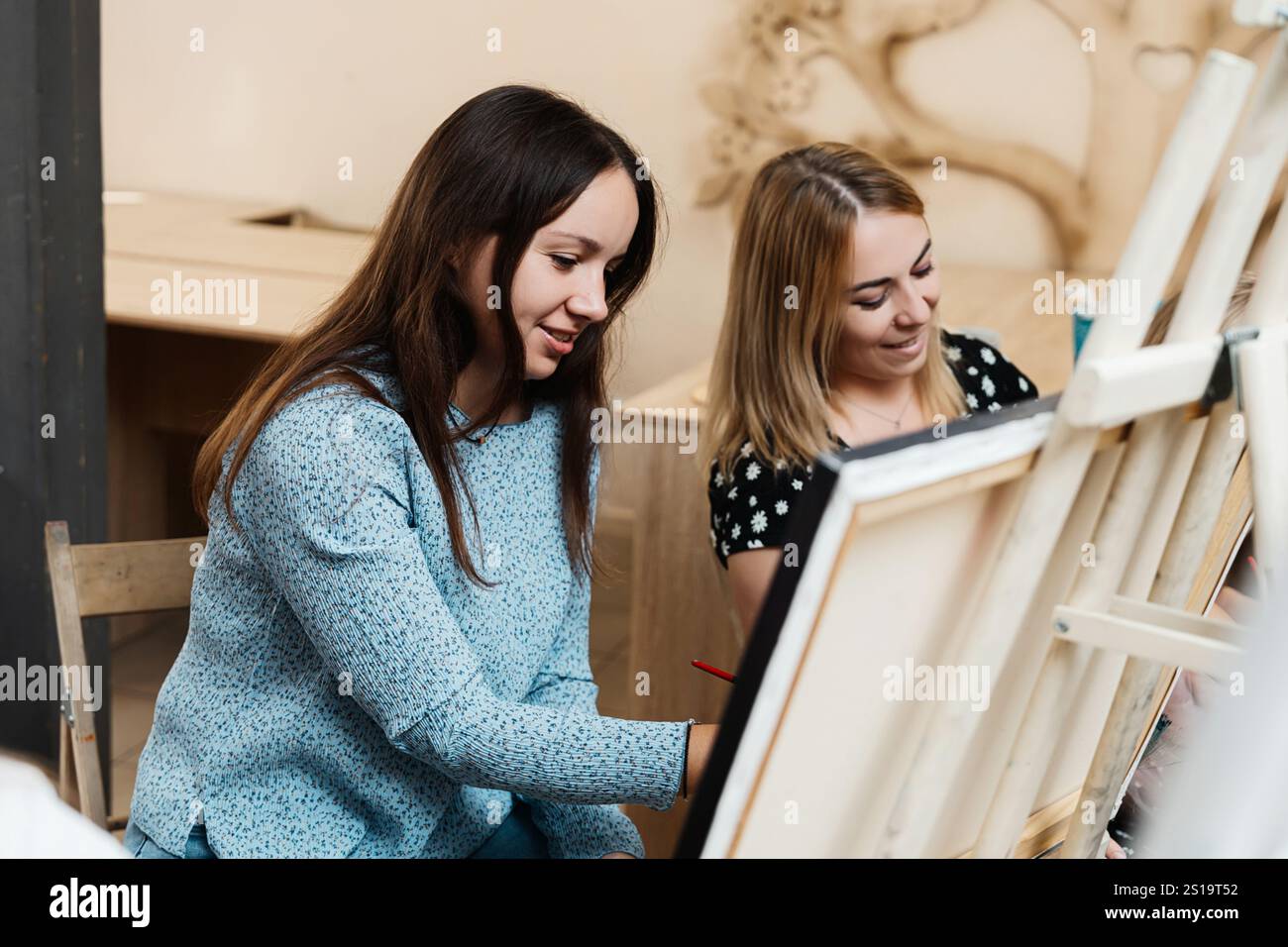 Two women enjoy a painting session in an art studio during daytime ...