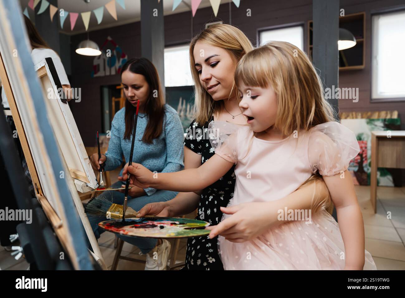 A mother and daughter create art together in a lively painting class ...