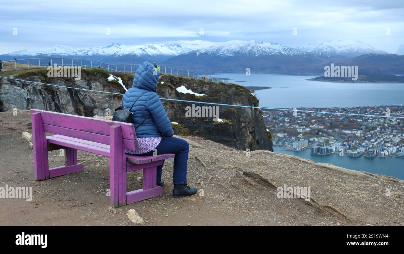 Lady sitting on a purple bench overlooking the city of Tromso, Norway ...