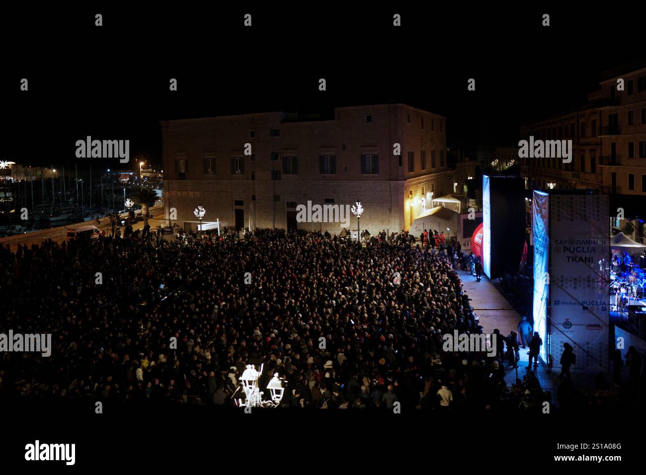 Trani, Italy. 31st Dec, 2024. A large crowd of people enjoy and sing ...