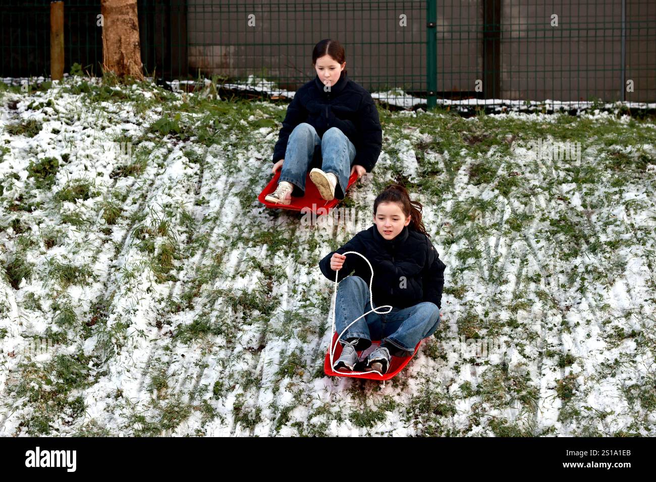 (left to right) twins Mia and Ava Clarke, 8, sled down a hill in the ...