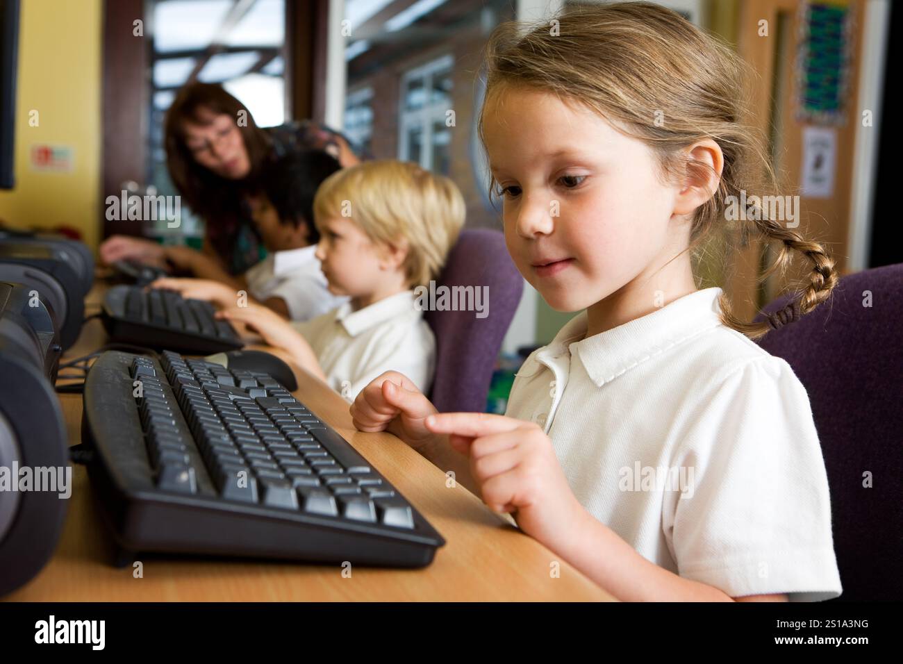 Elementary School: Keyboard Skills. A young junior age girl concentrating on developing her ...