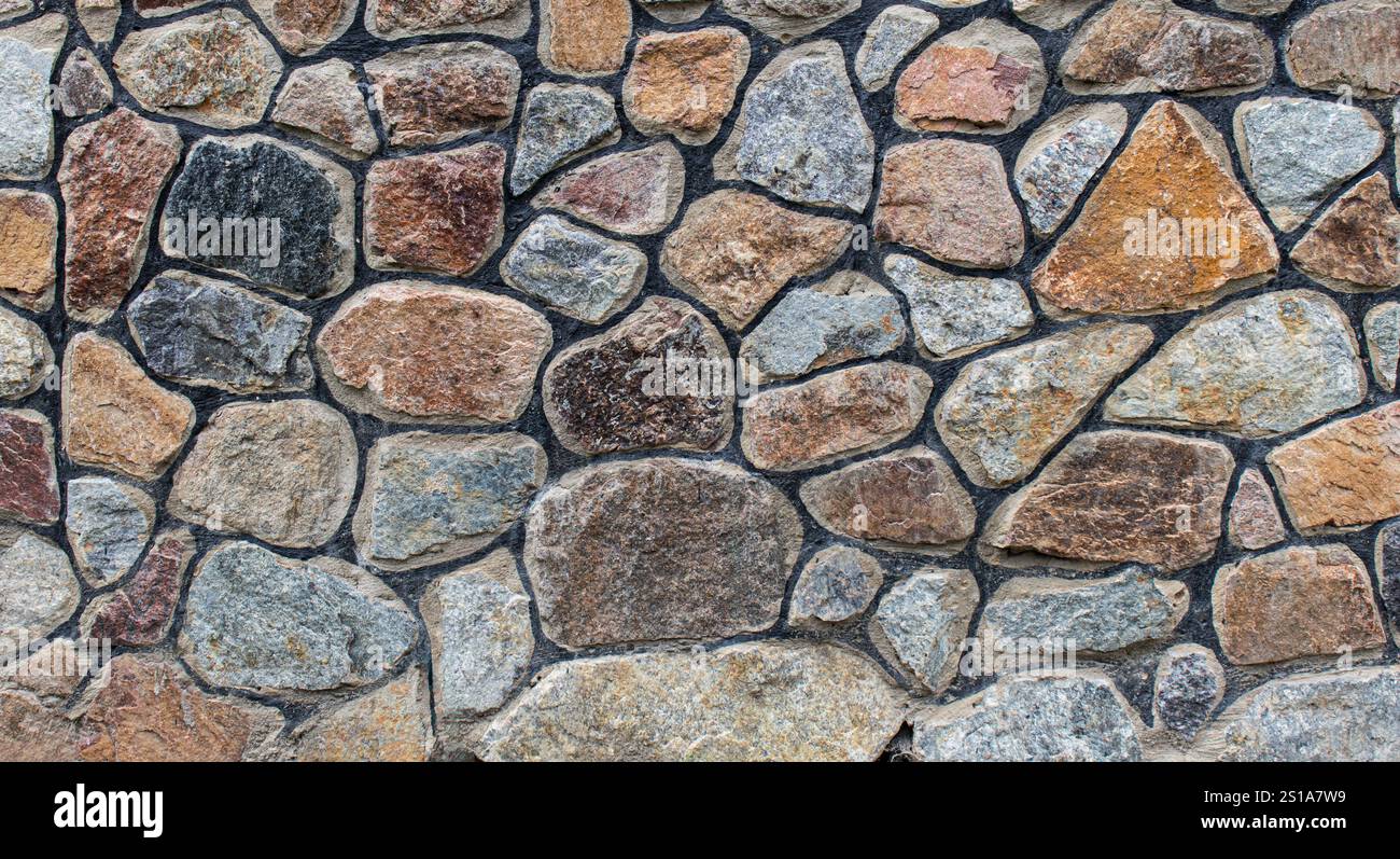 A decorative stone wall featuring multicolored stones and rugged mortar ...