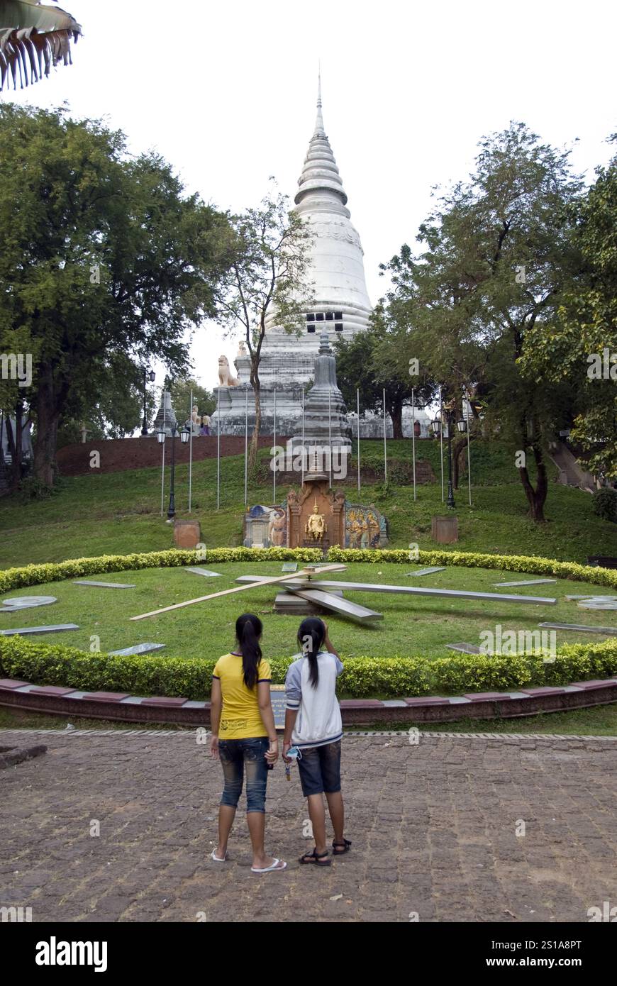 Two young girls look at a large clock built into a garden at Wat Phnom ...