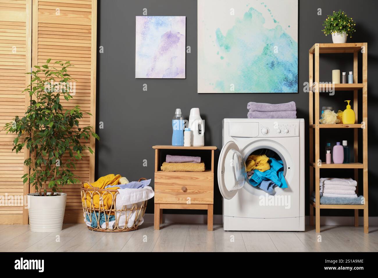 Washing machine, detergents and basket with laundry in room Stock Photo ...