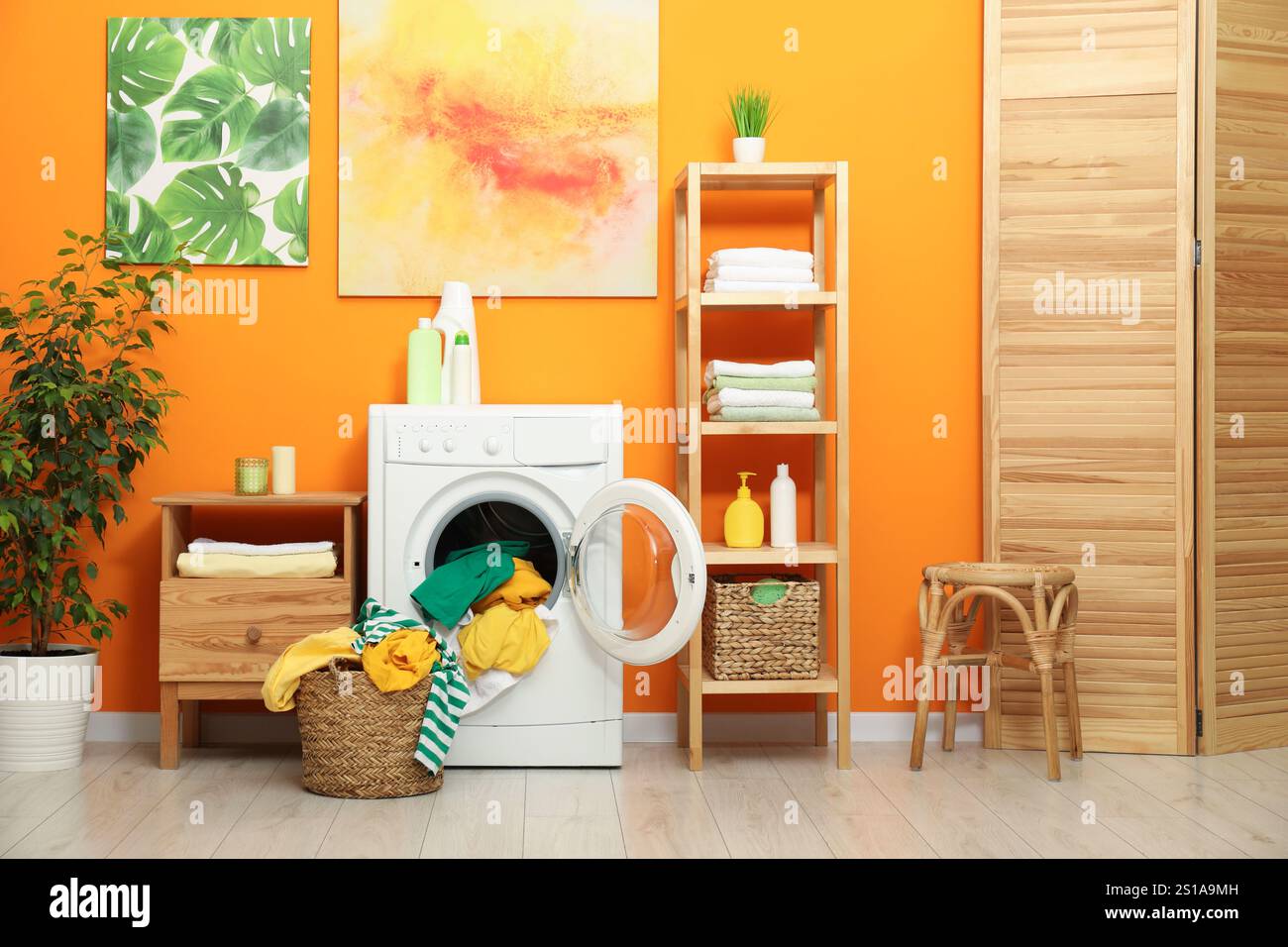 Washing machine, detergents and basket with laundry in room Stock Photo ...