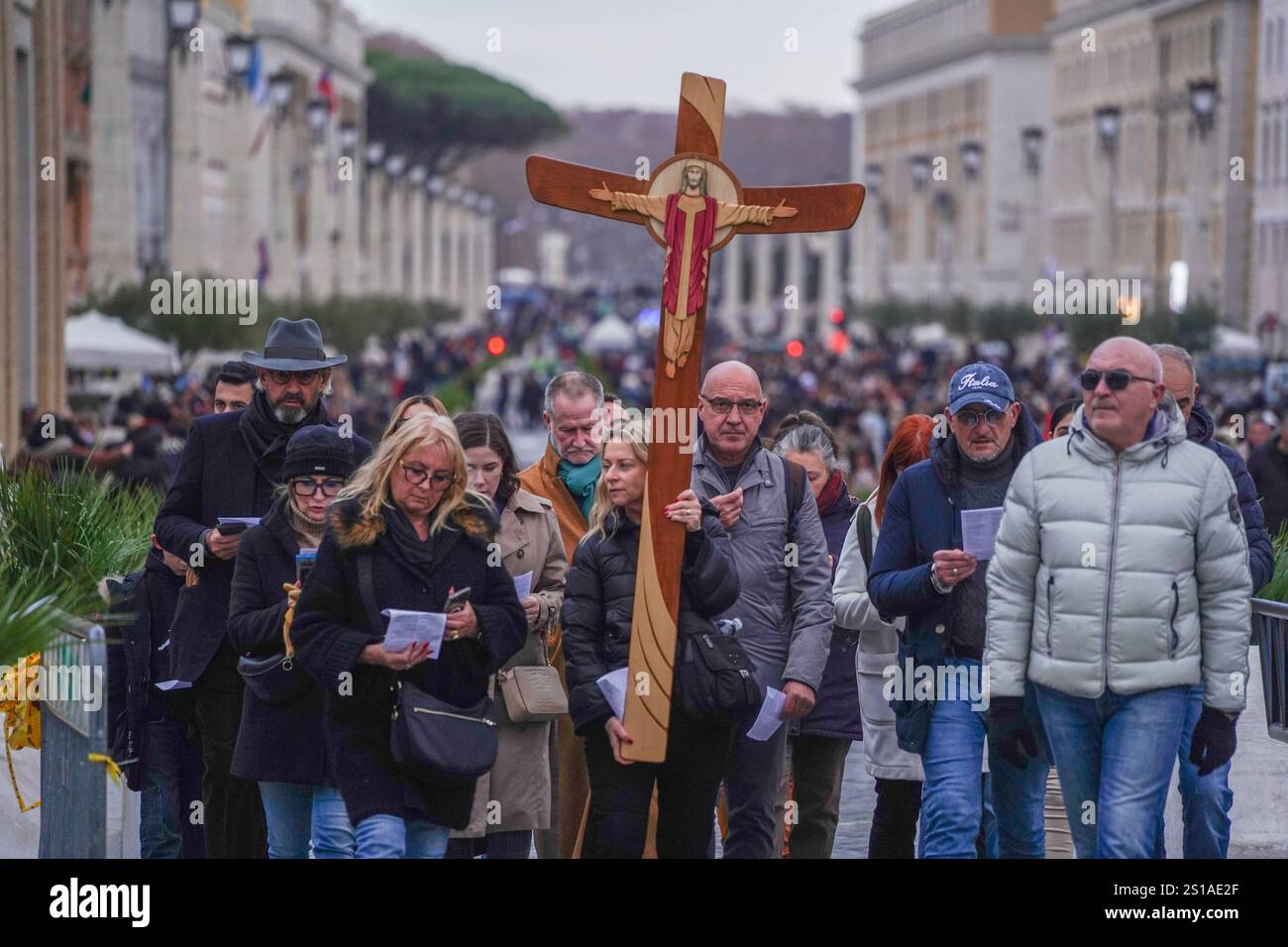 Rome, Italy 2 January 2025 Devout pilgrims carry a wooden cross at the Vatican as they walk ...