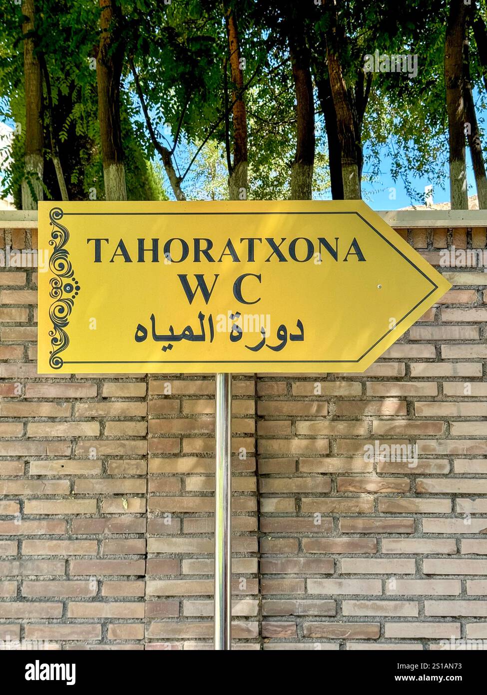 Yellow restroom sign in three languages against a brick wall Stock ...