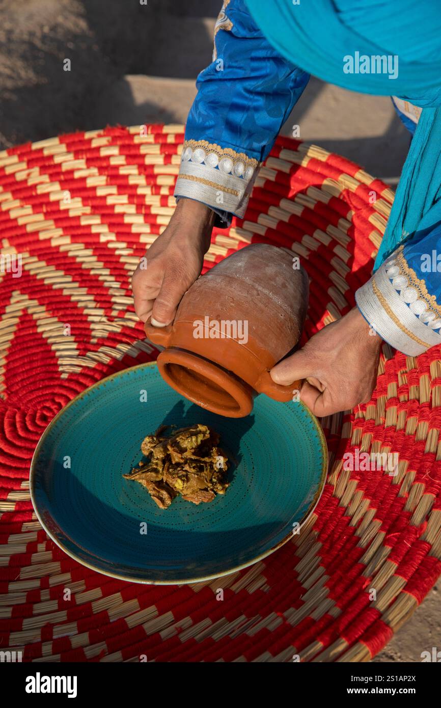 Morocco, Agafay, man in sahariand djellaba serving tanjia, a ...