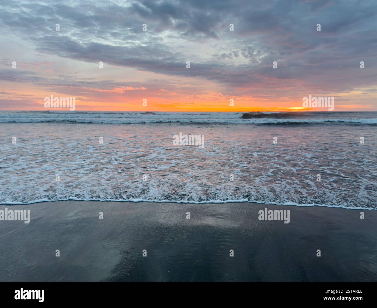 Waves gently wash ashore as vibrant sunset paints sky with warm colors ...