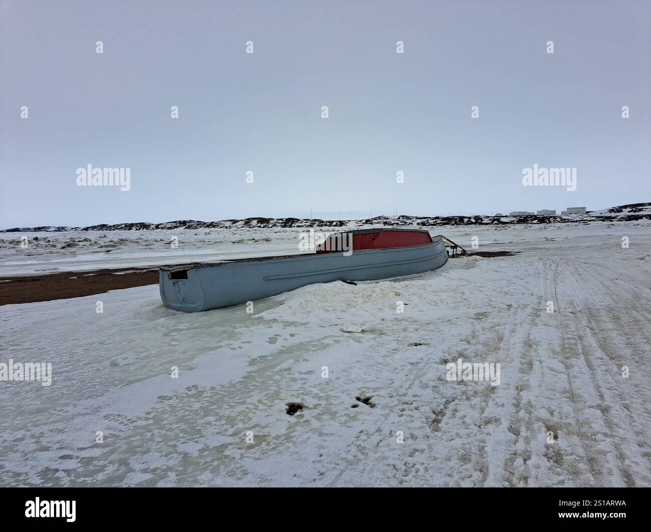 Grey and red wooden boat stored on the beach on Frobisher Bay in Iqaluit, Nunavut, Canada Stock ...