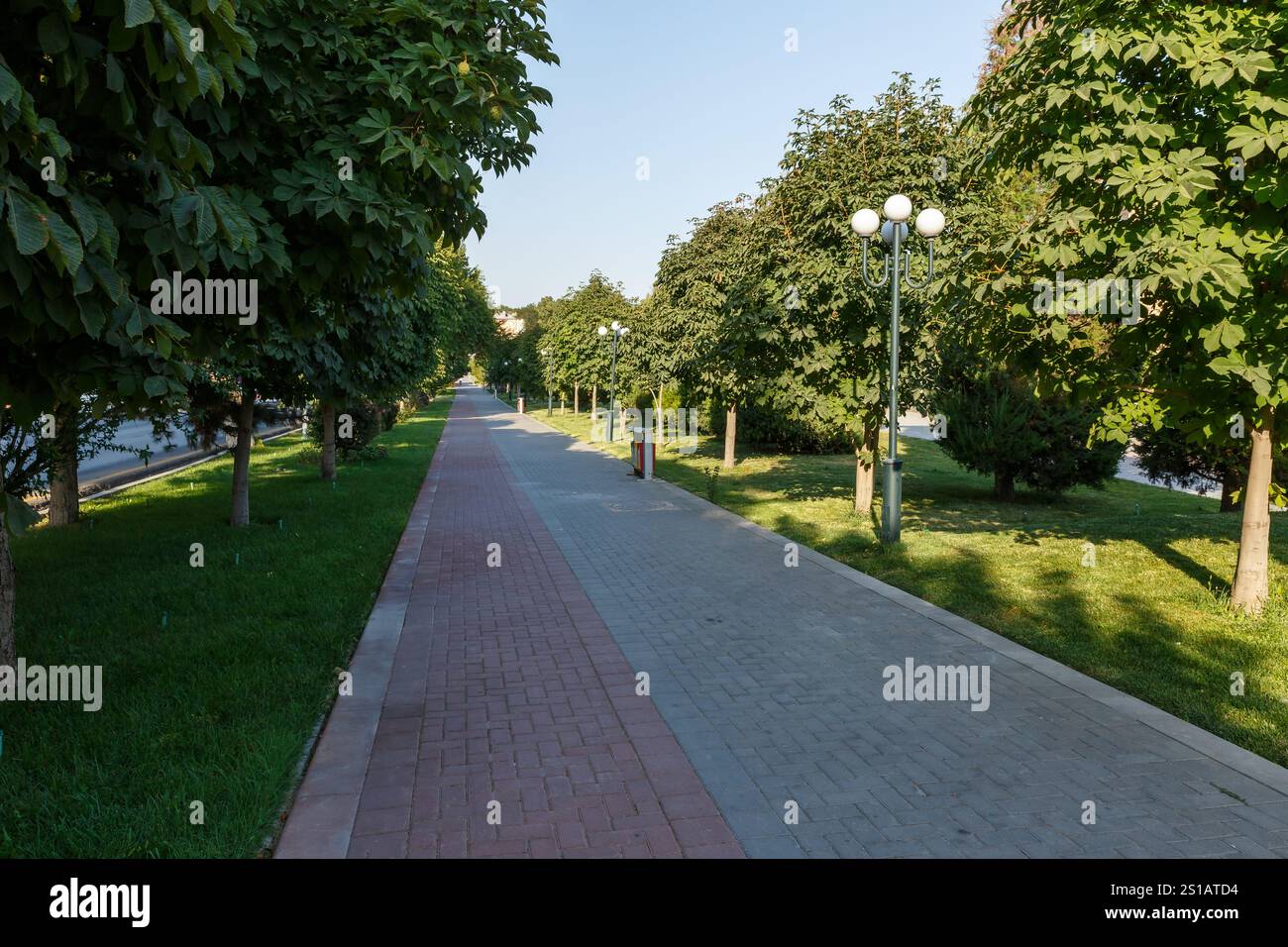 A peaceful walkway in Haji Muin Shukrulla Park features lush trees on ...