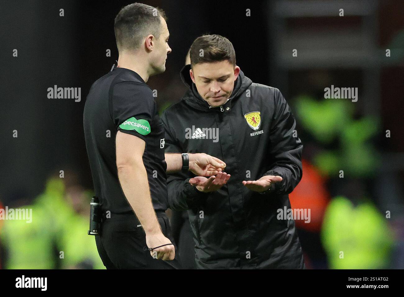 Referee Don Robertson (left) passes an object that was thrown from the ...