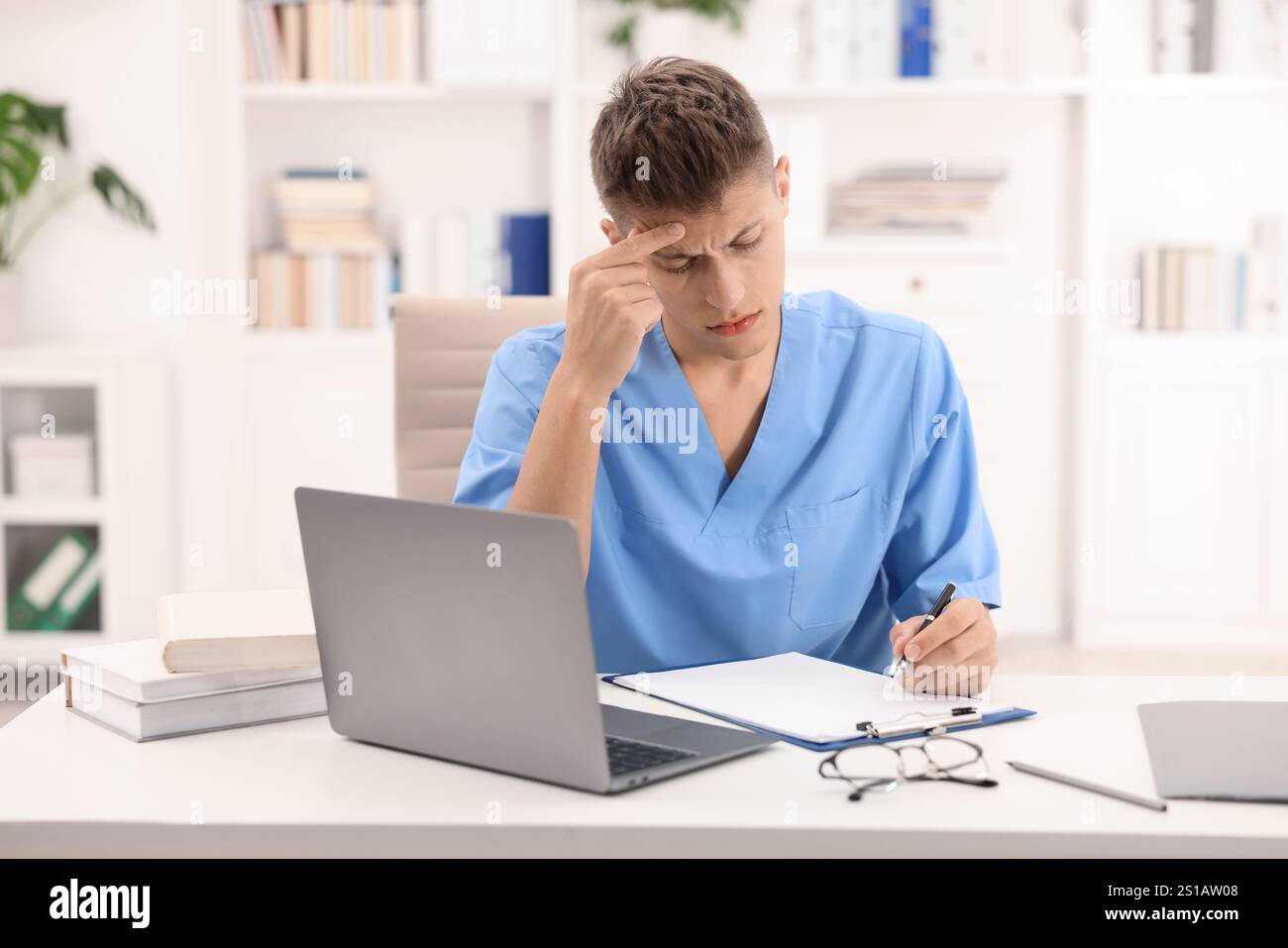 Medical student in uniform studying at table indoors Stock Photo - Alamy