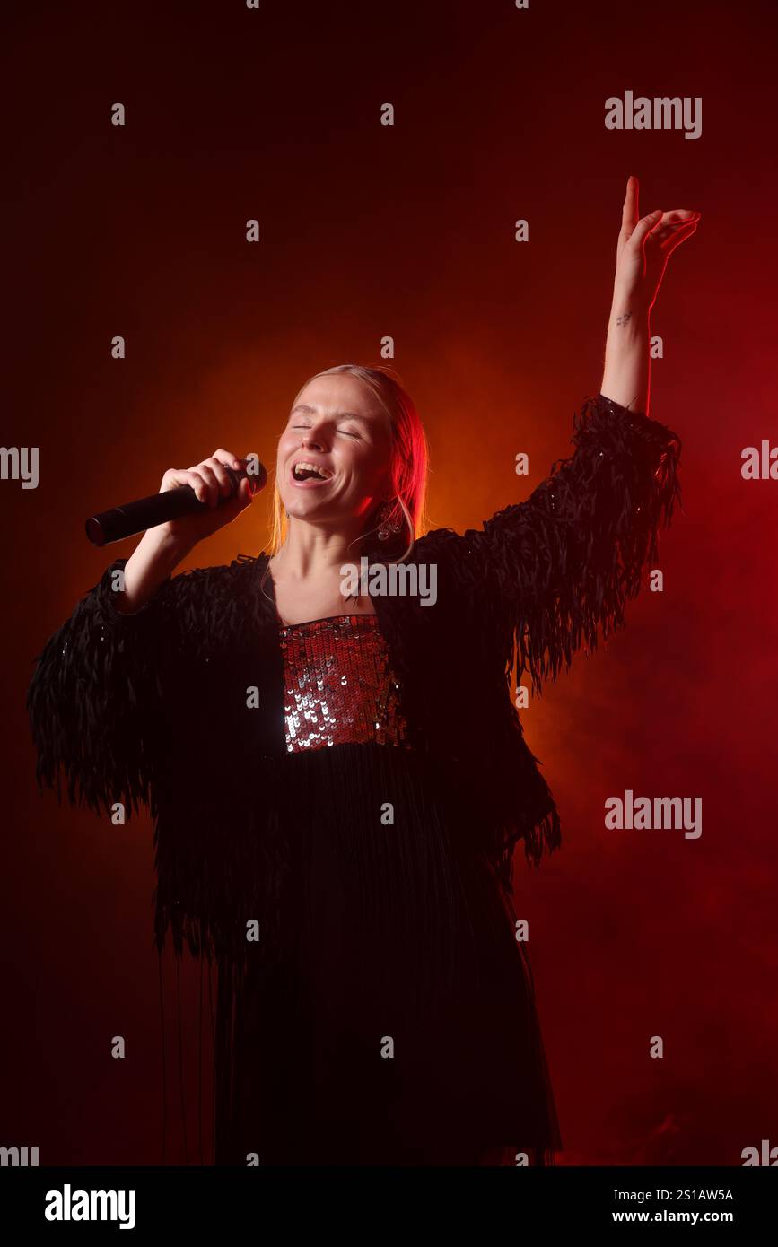 Beautiful singer performing on dark background with orange light Stock ...