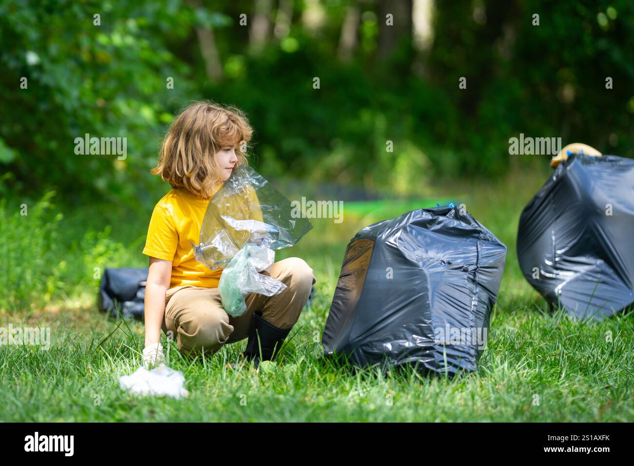 Kid in rubber gloves with trash bag clean up garbage on forest outdoor ...