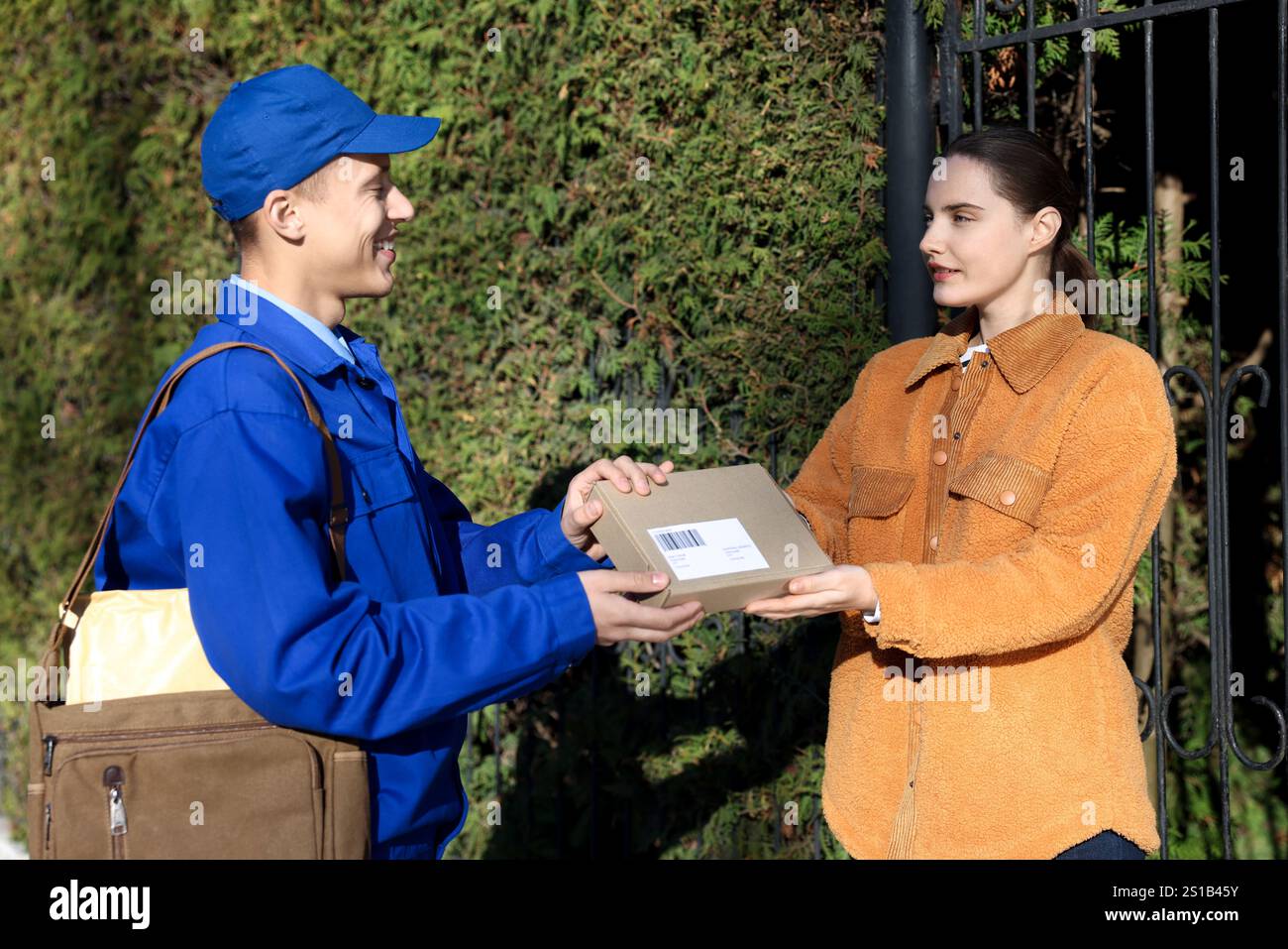 Woman receiving parcel from postman outdoors. Mail service Stock Photo ...